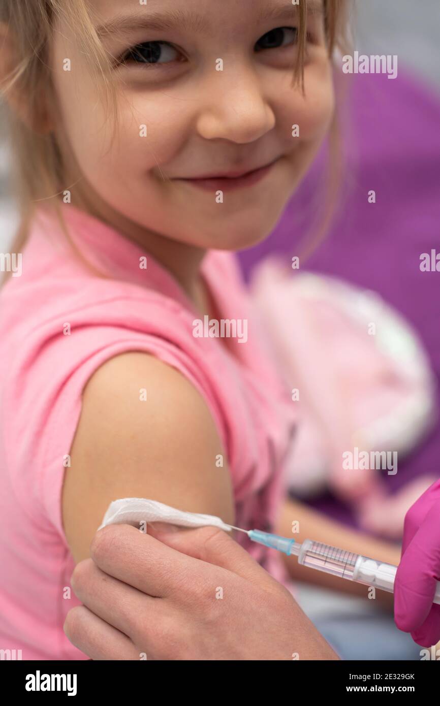 The nurse gently inserts the needle into the little girl's arm. The ...
