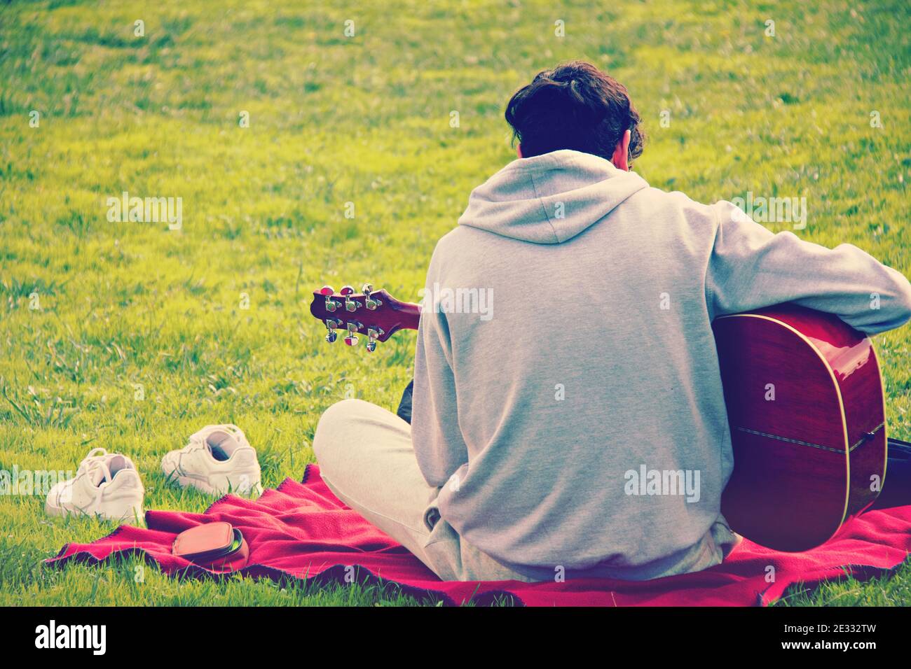 shot of a college student while playing guitar in a park, concept of ...
