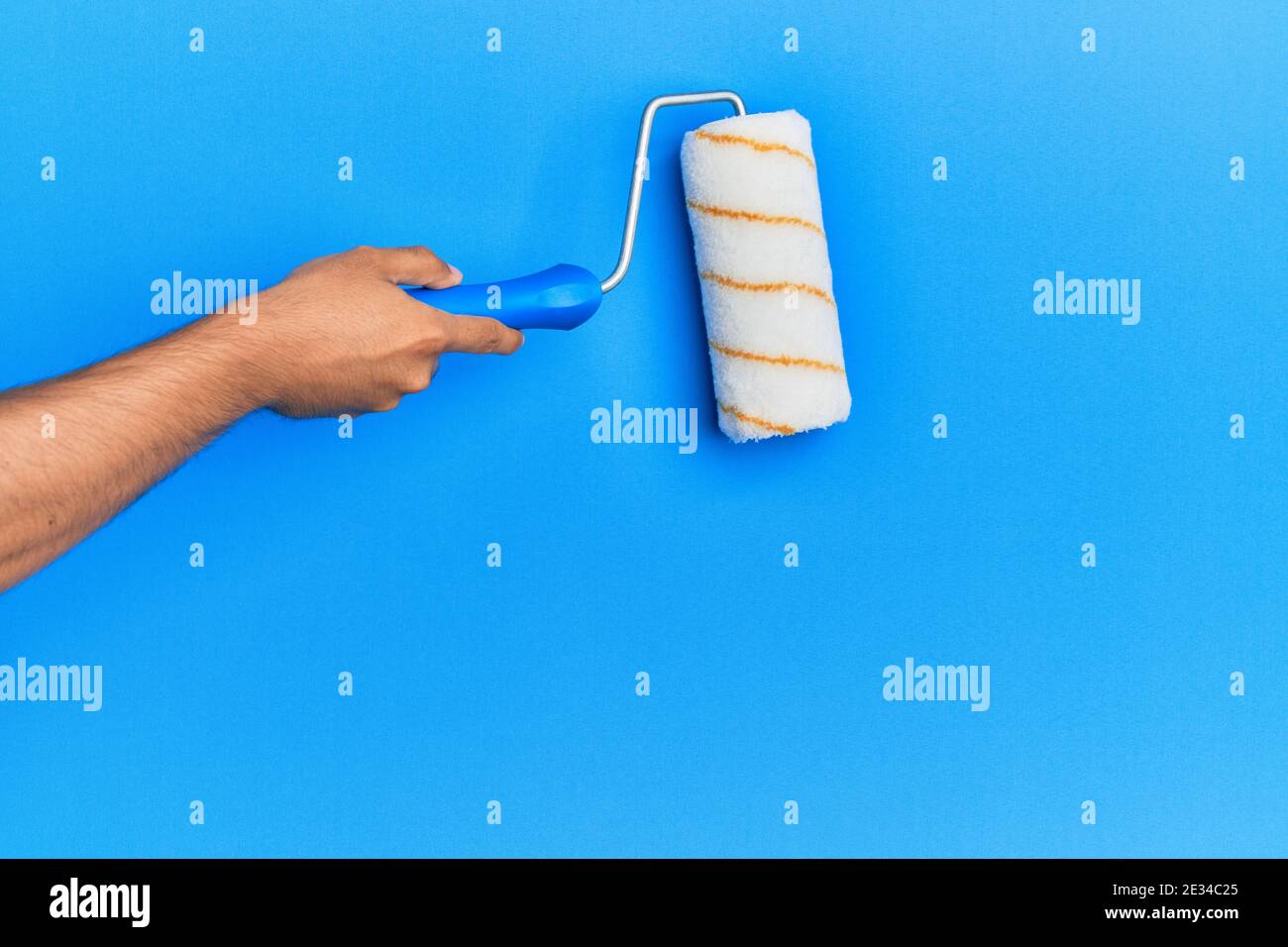 Hand of hispanic man painting blue wall using paint roller Stock Photo ...