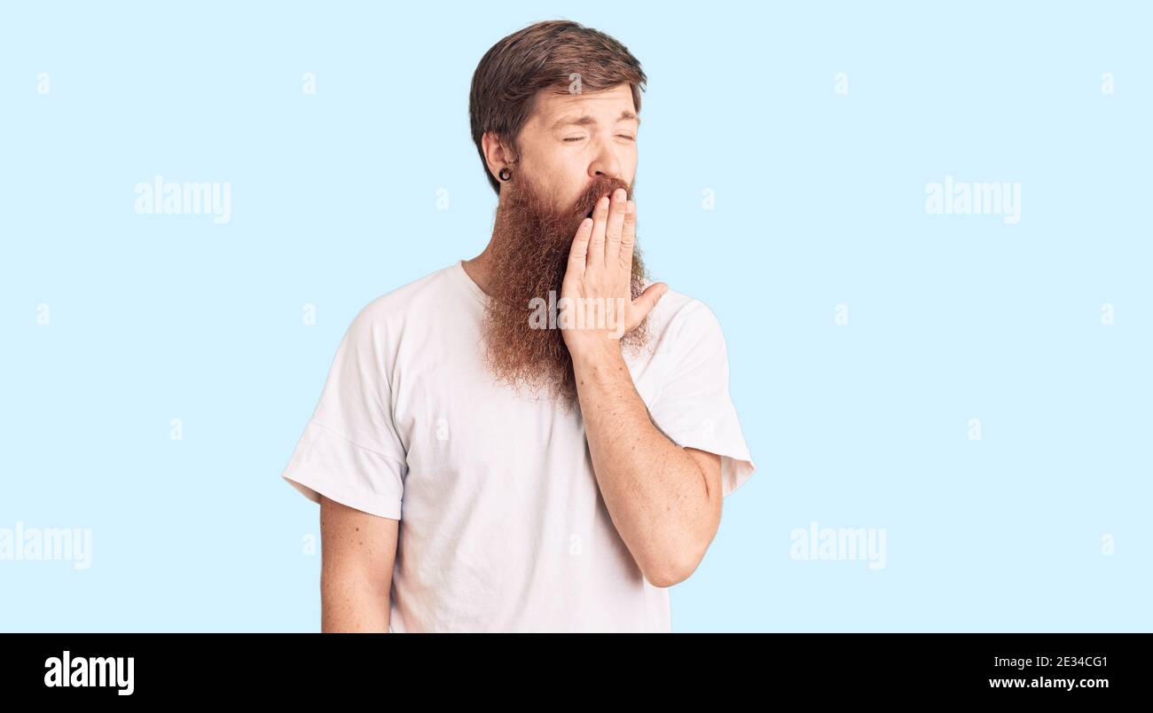 Handsome young red head man with long beard wearing casual white tshirt ...