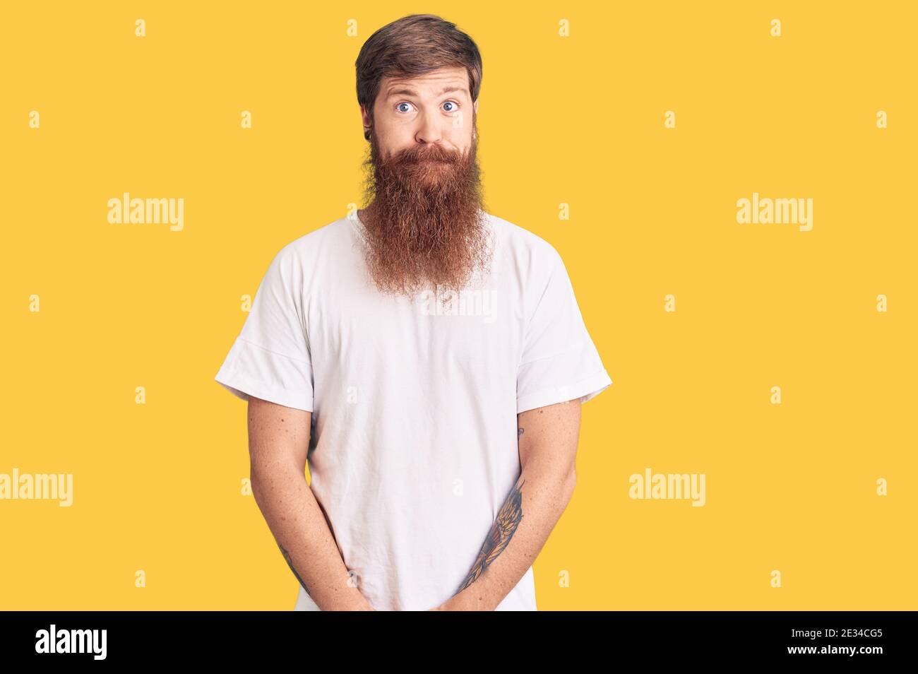 Handsome young red head man with long beard wearing casual white tshirt ...