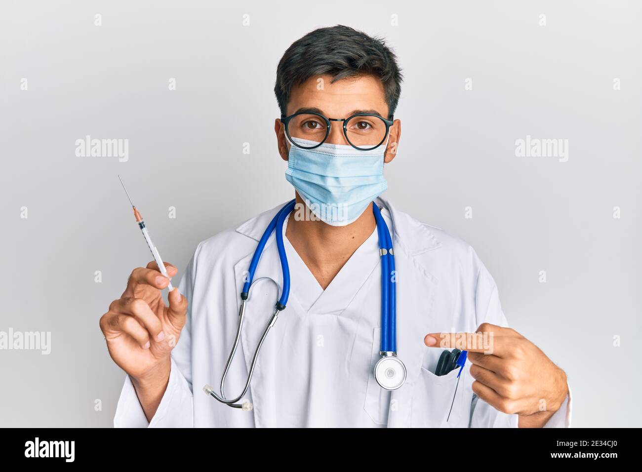 Young handsome man wearing doctor uniform and medical mask holding ...