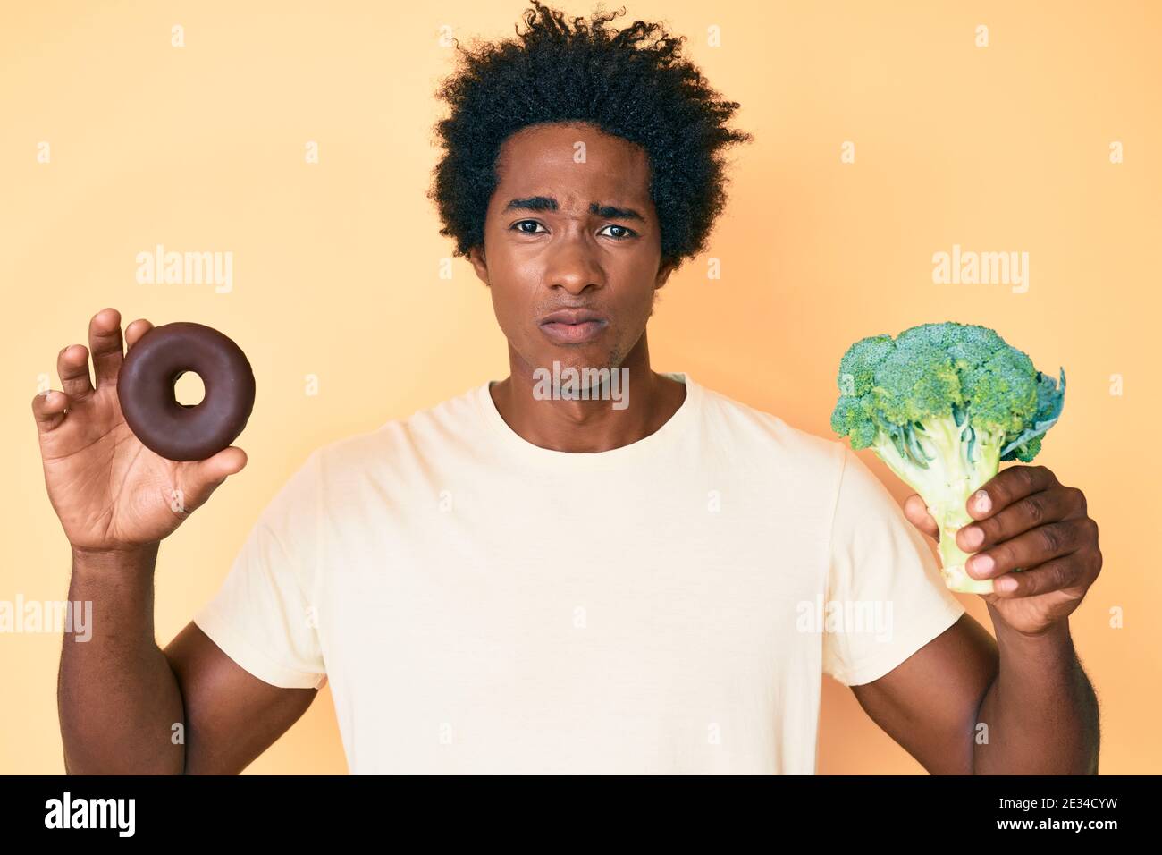 Handsome african american man with afro hair holding broccoli and ...