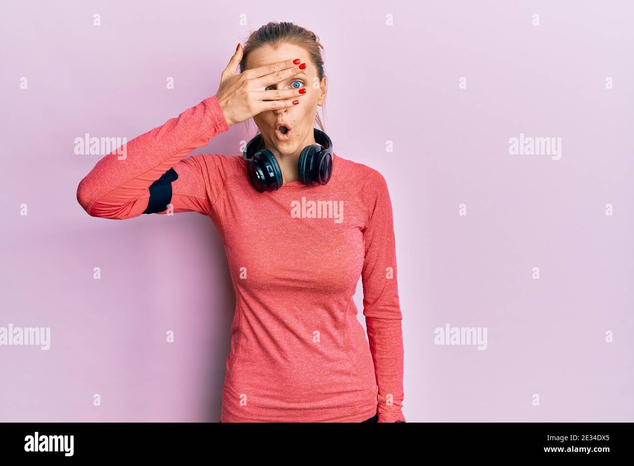 Beautiful caucasian woman wearing sportswear and arm band peeking in ...