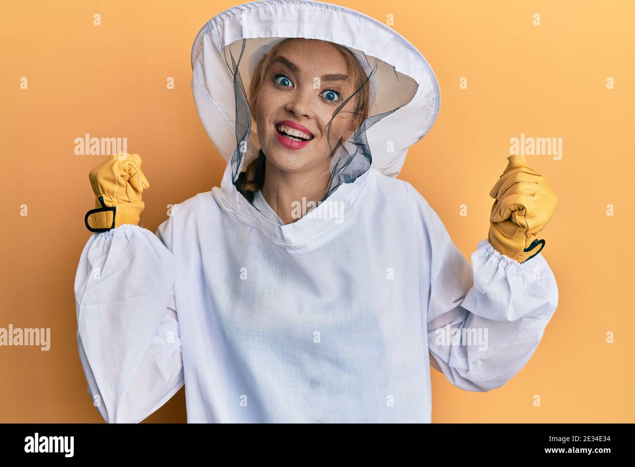Beautiful blonde caucasian woman wearing protective beekeeper uniform ...
