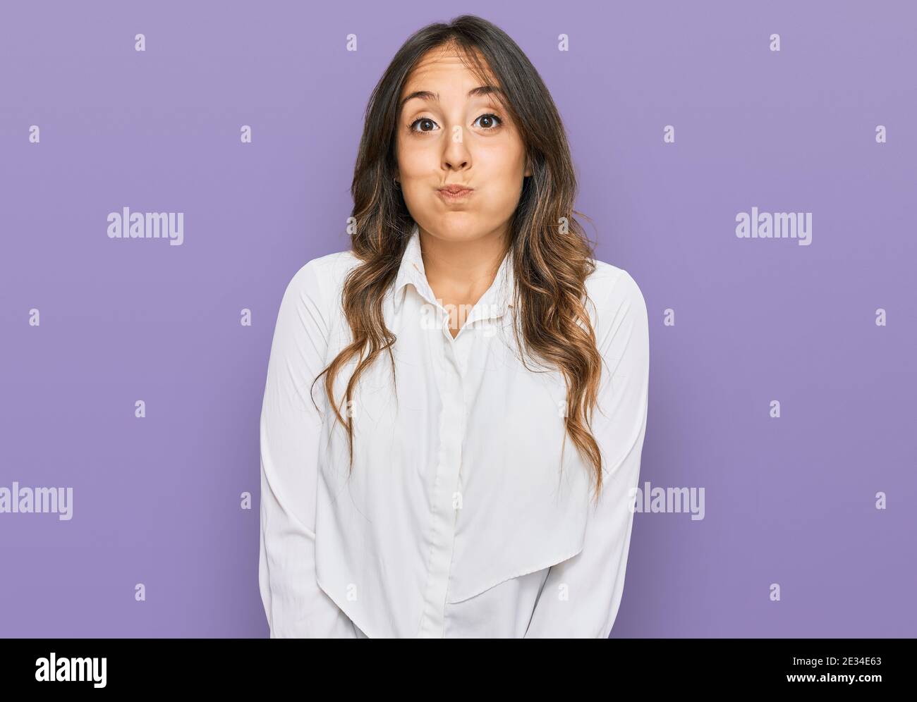 Young brunette woman wearing casual clothes puffing cheeks with funny ...