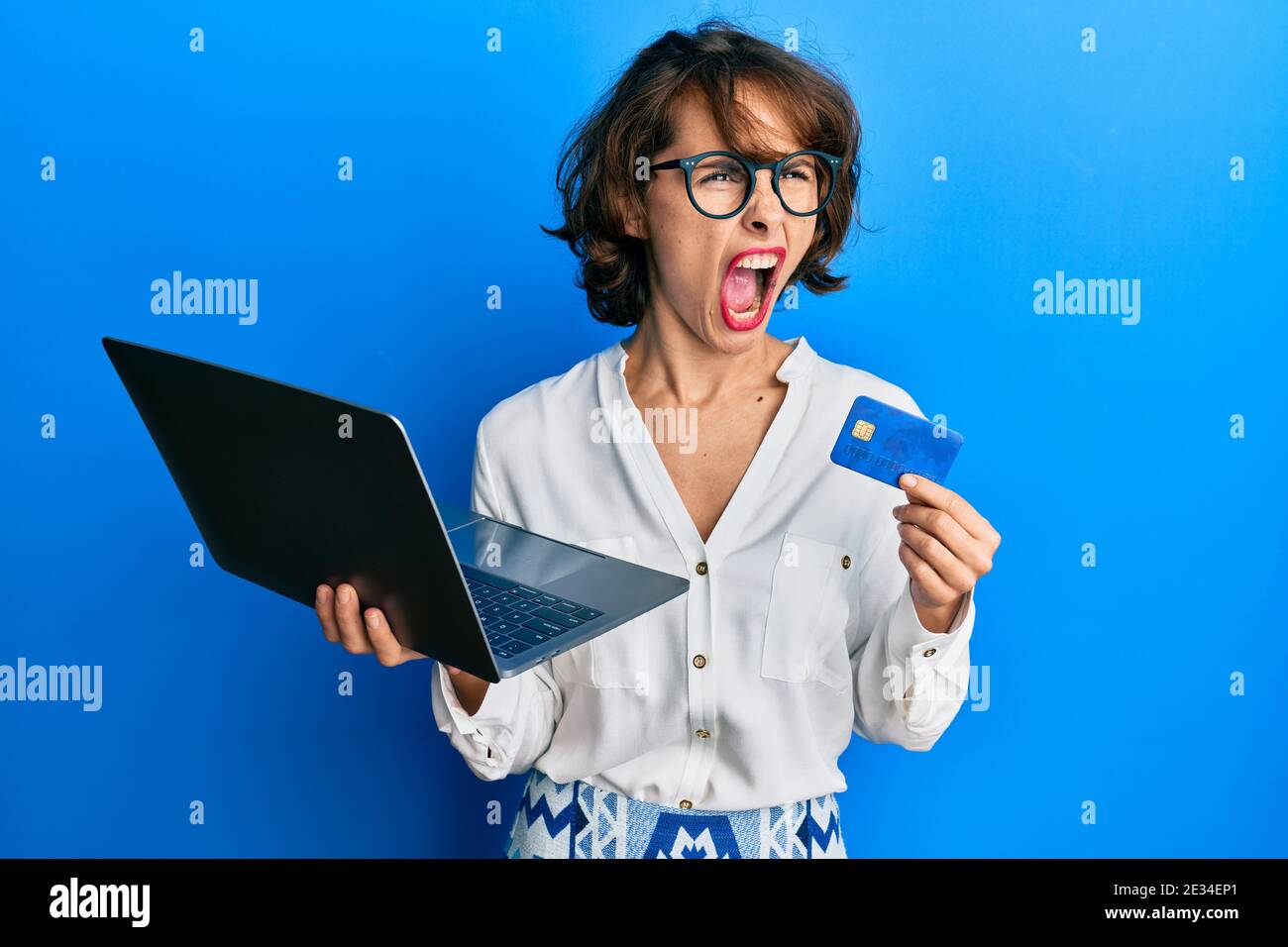 Young brunette woman wearing business style holding laptop and credit ...