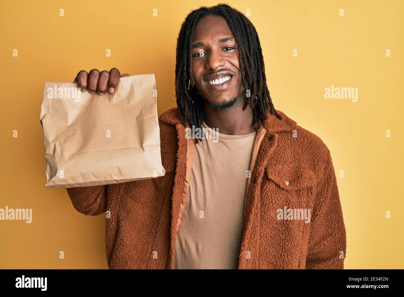 African american man with braids holding take away paper bag looking ...