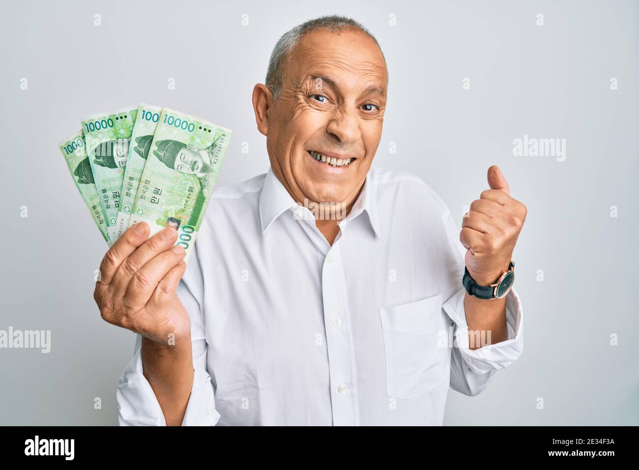 Handsome senior man holding 10000 south korean won banknotes screaming ...