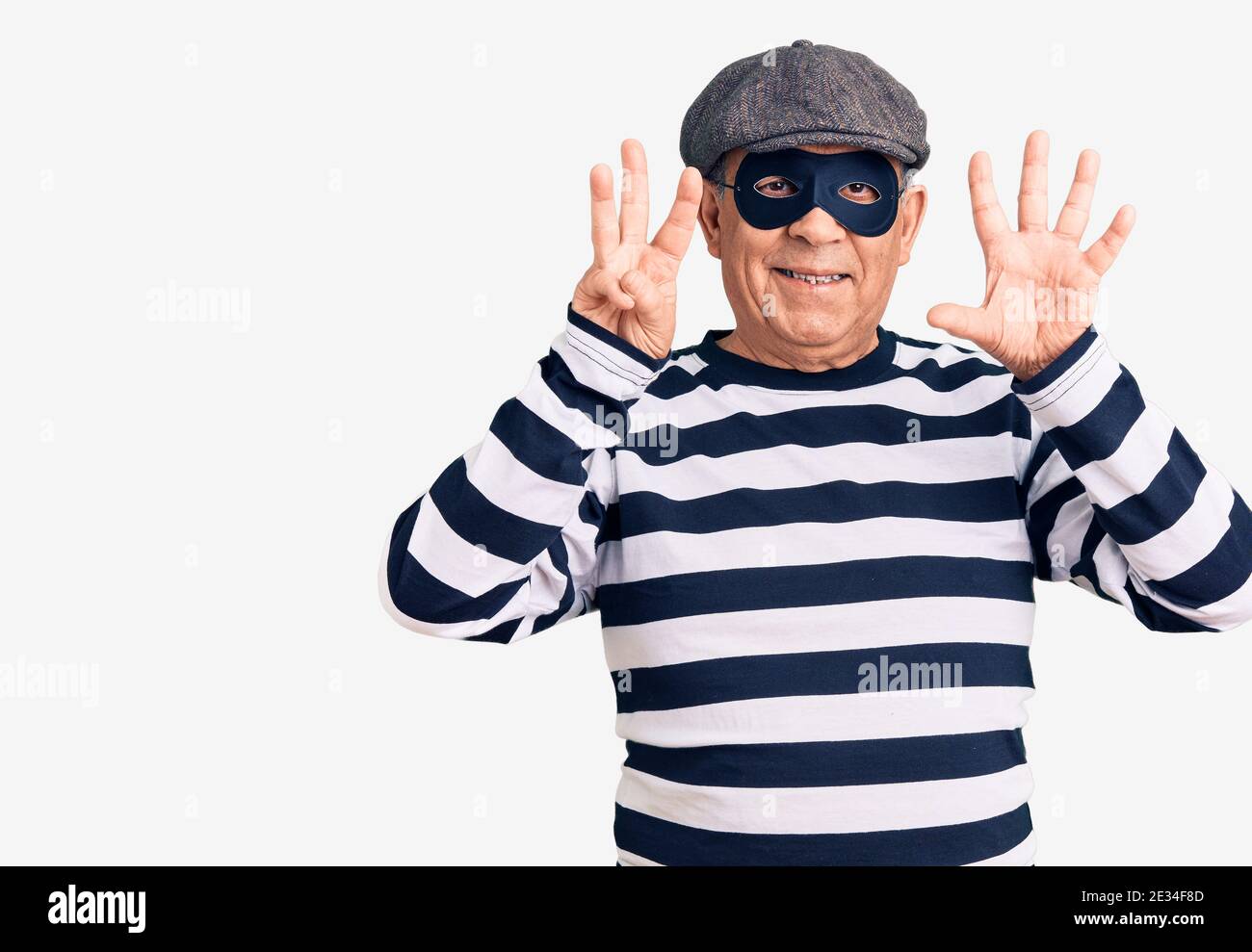Senior handsome man wearing burglar mask and t-shirt showing and ...