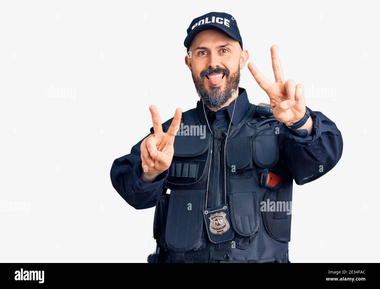 Young handsome man wearing police uniform smiling with tongue out ...