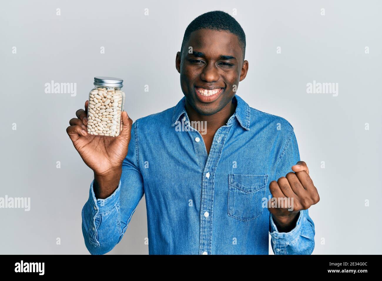 Young african american man holding jar of beans screaming proud ...