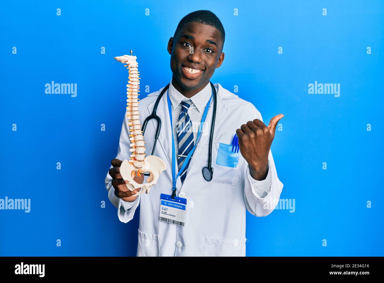 Young african american doctor man holding anatomical model of spinal ...