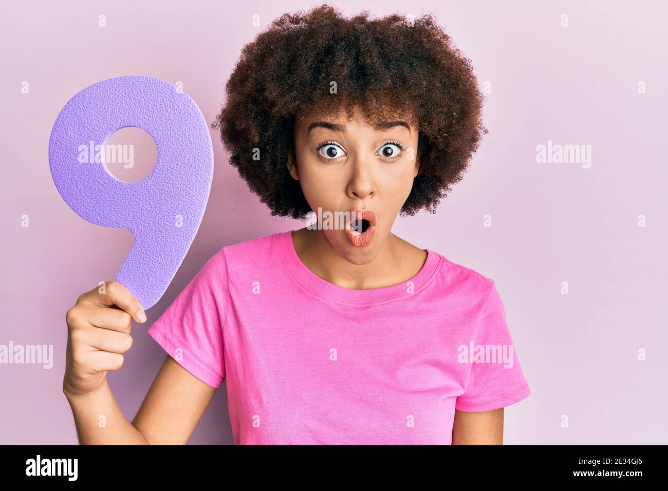 Young hispanic girl holding number nine scared and amazed with open ...