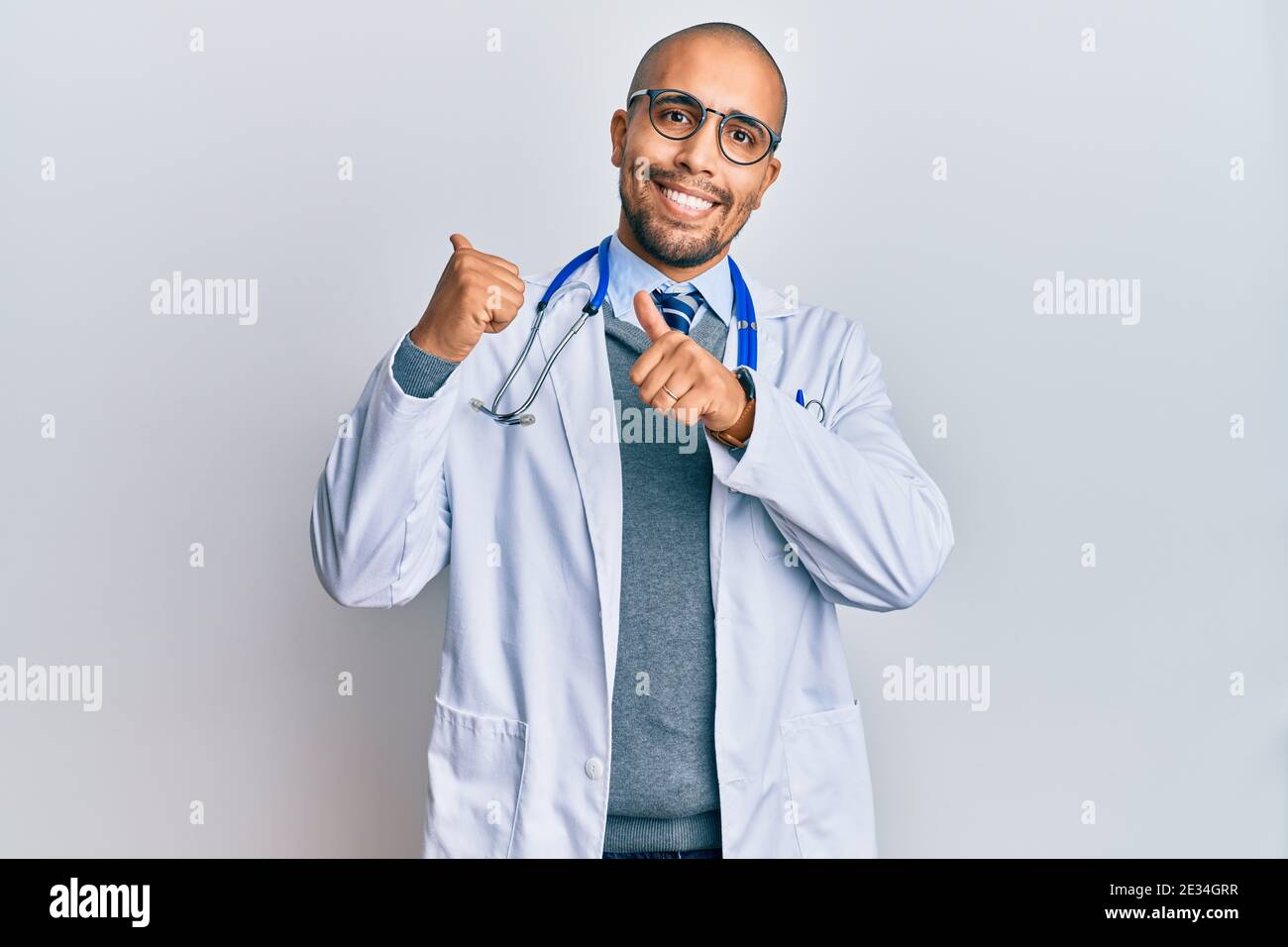 Hispanic adult man wearing doctor uniform and stethoscope pointing to ...