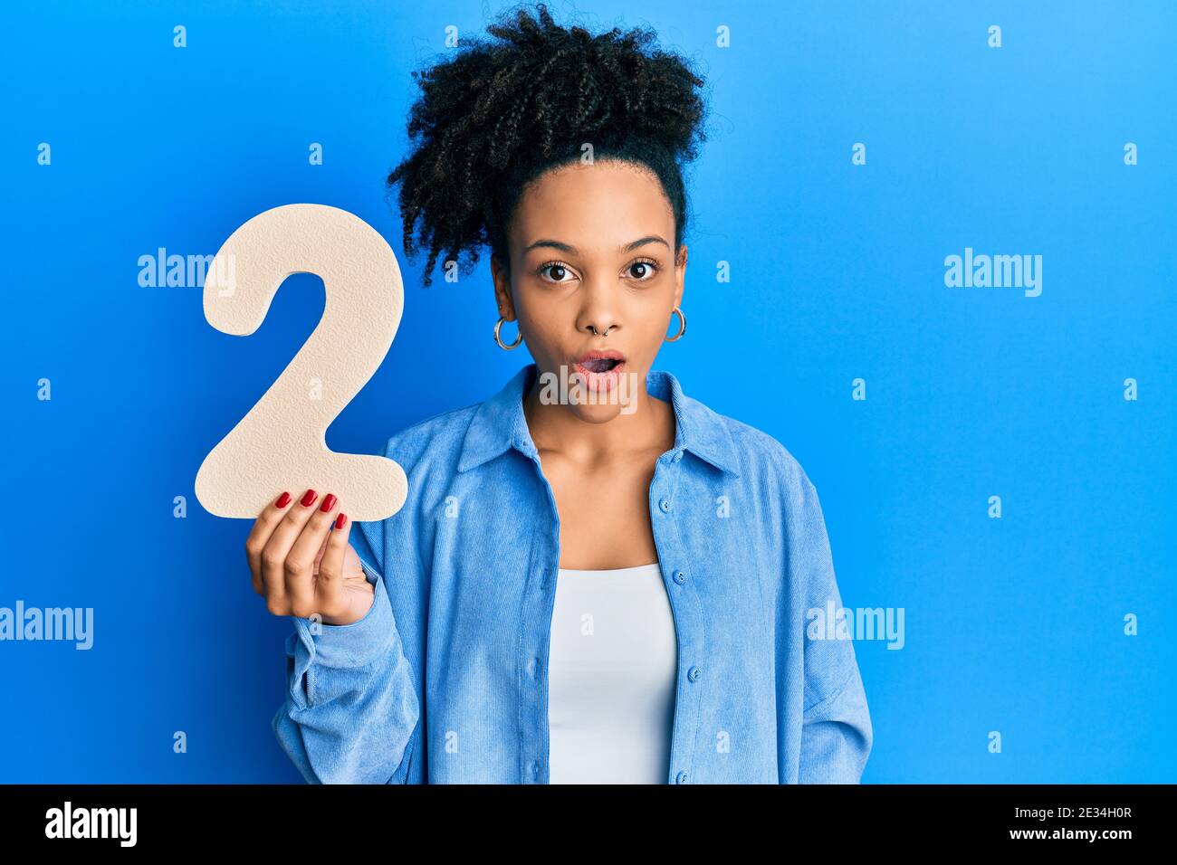 Young african american girl holding number two scared and amazed with ...