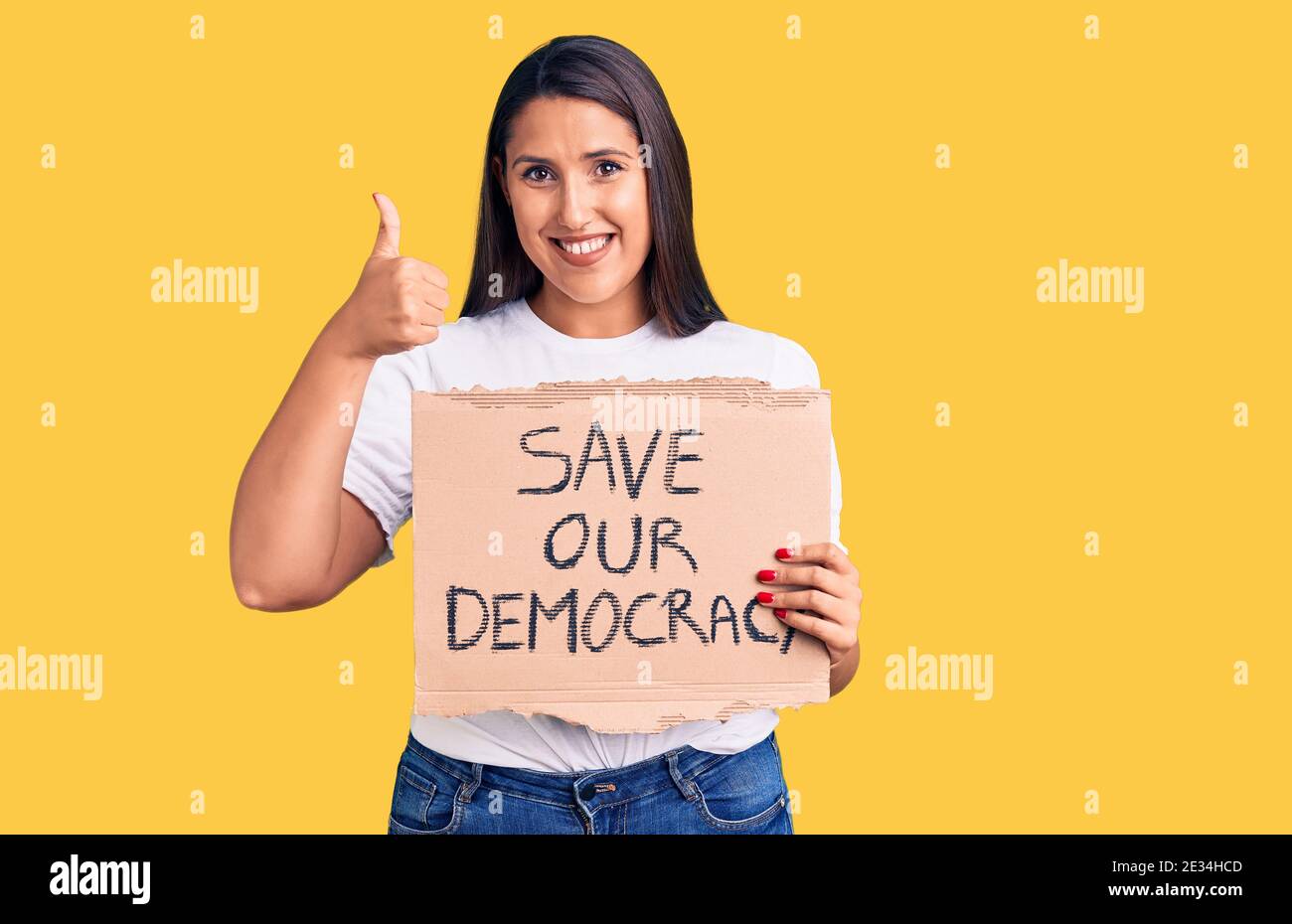 Young beautiful woman holding save our democracy cardboard banner ...