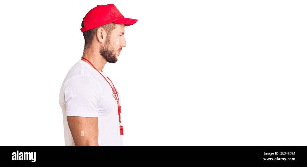 Young caucasian man wearing lifeguard t shirt holding whistle looking ...