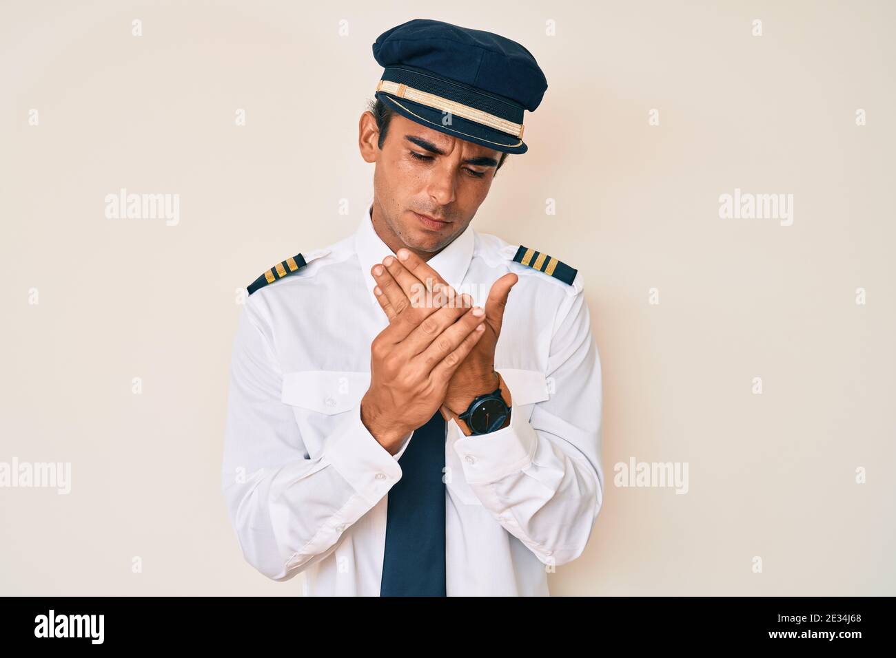 Young hispanic man wearing airplane pilot uniform suffering pain on ...