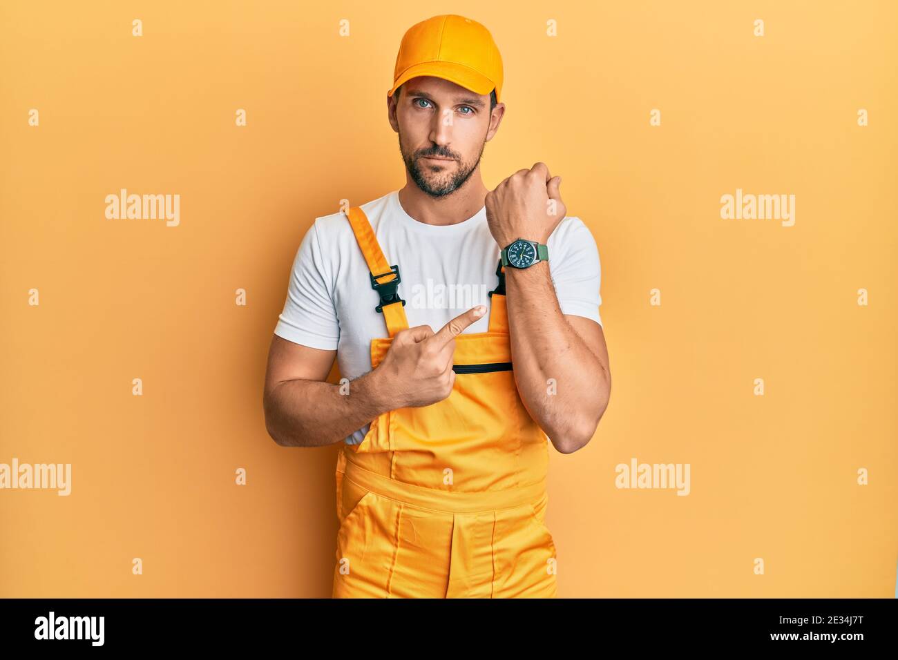 Young handsome man wearing handyman uniform over yellow background in ...