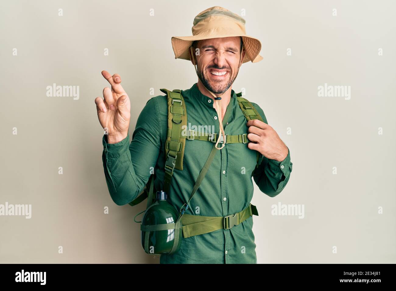 Handsome man with beard wearing explorer hat and backpack gesturing ...