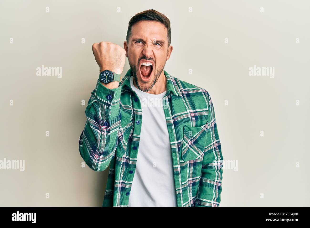 Handsome man with beard wearing casual clothes angry and mad raising ...