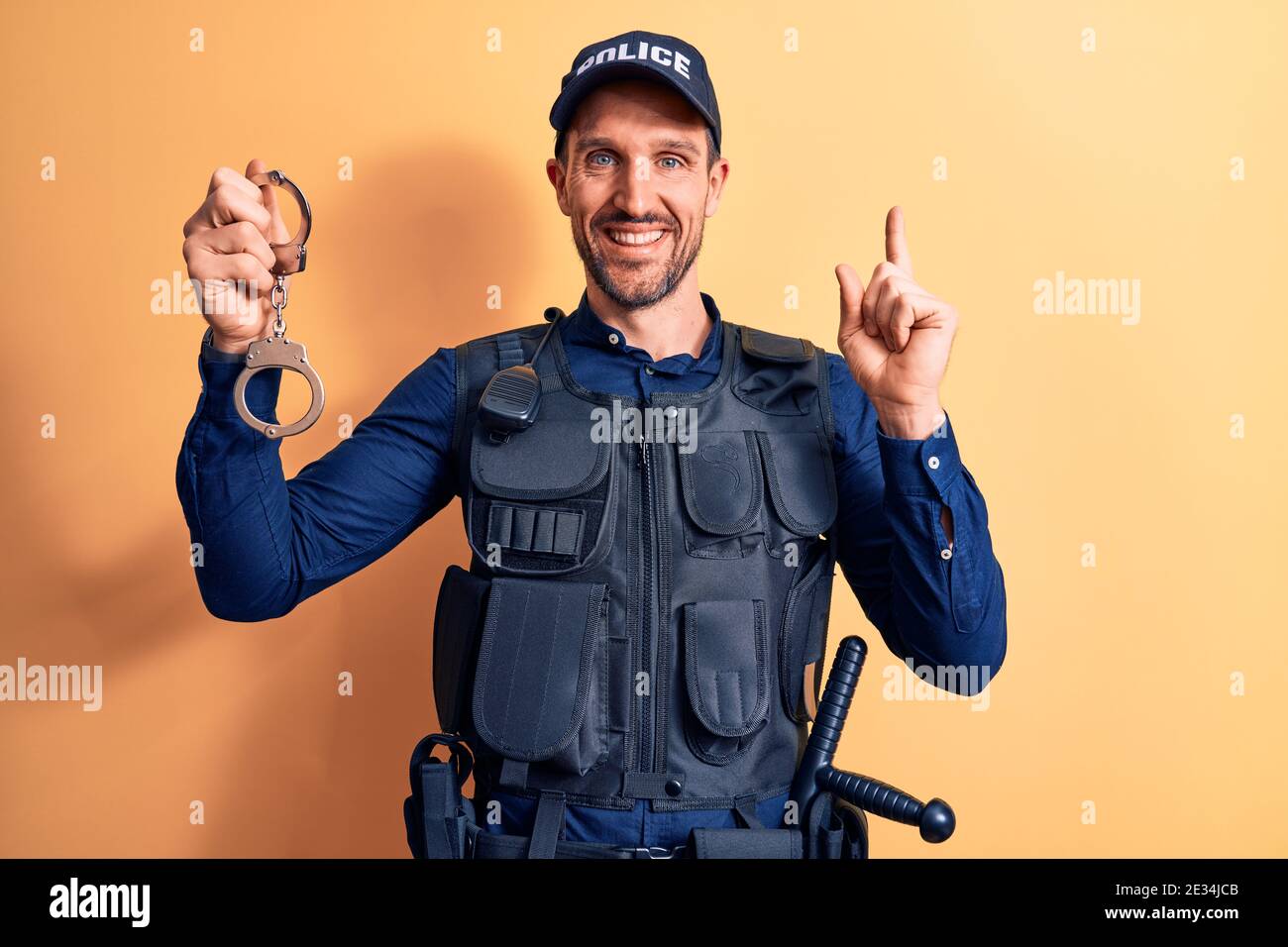 Handsome policeman wearing uniform and bulletprof holding handcuffs ...
