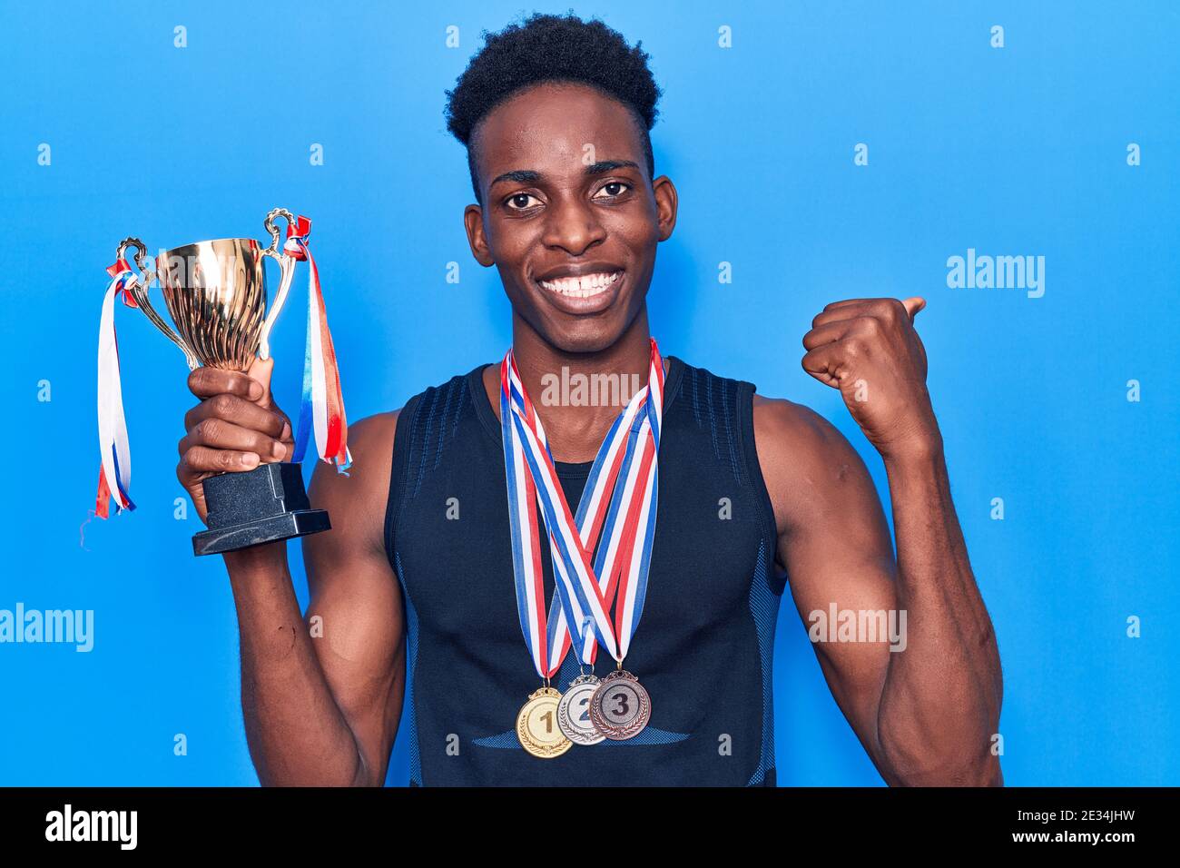Young african american man holding champion trophy wearing medals ...