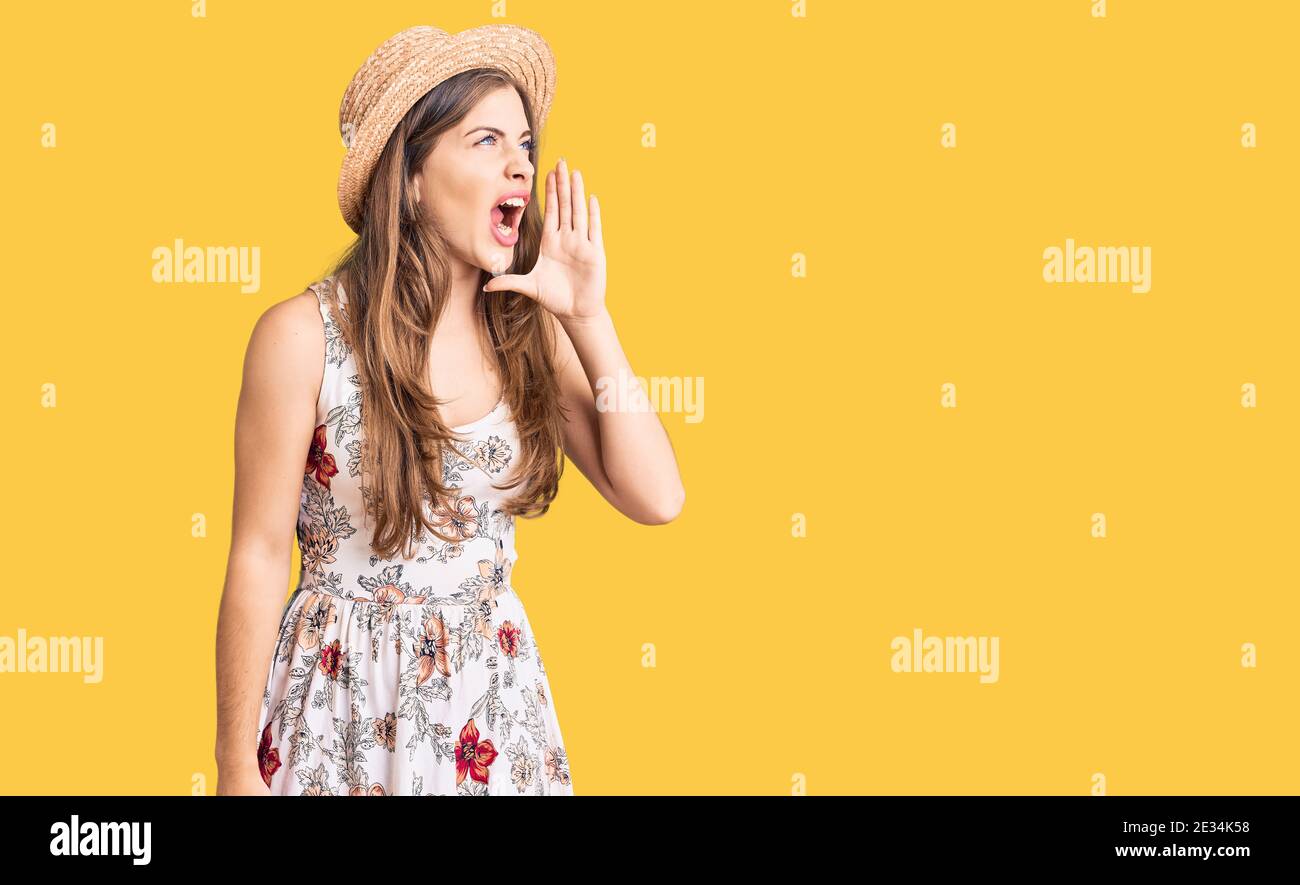 Beautiful caucasian young woman wearing summer hat shouting and ...