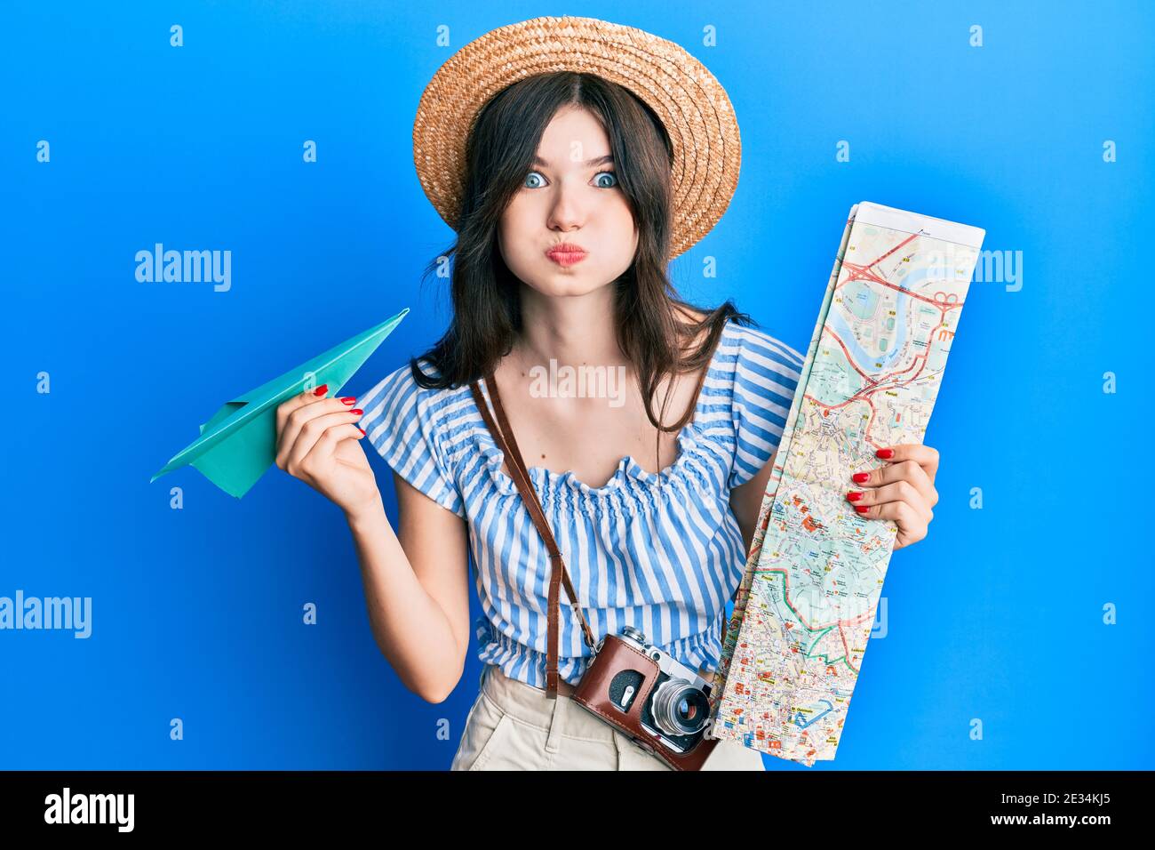 Young beautiful caucasian girl holding paper plane and city map puffing ...