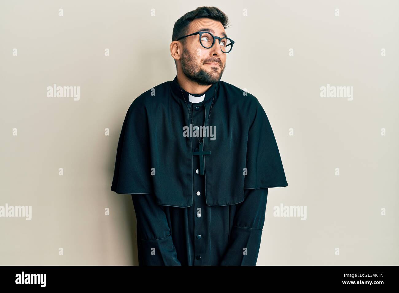Young hispanic man wearing priest uniform standing over white ...