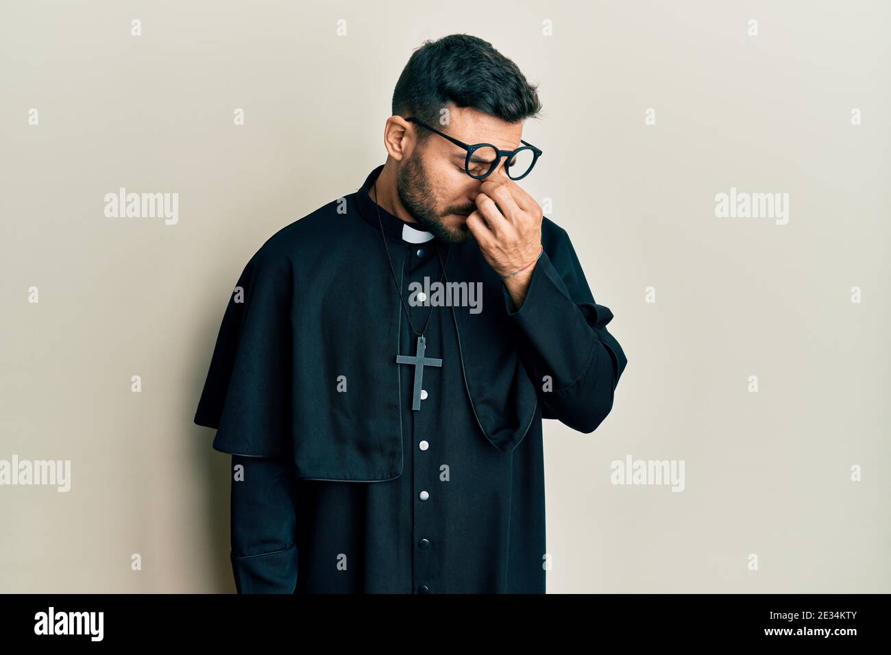 Young hispanic man wearing priest uniform standing over white ...