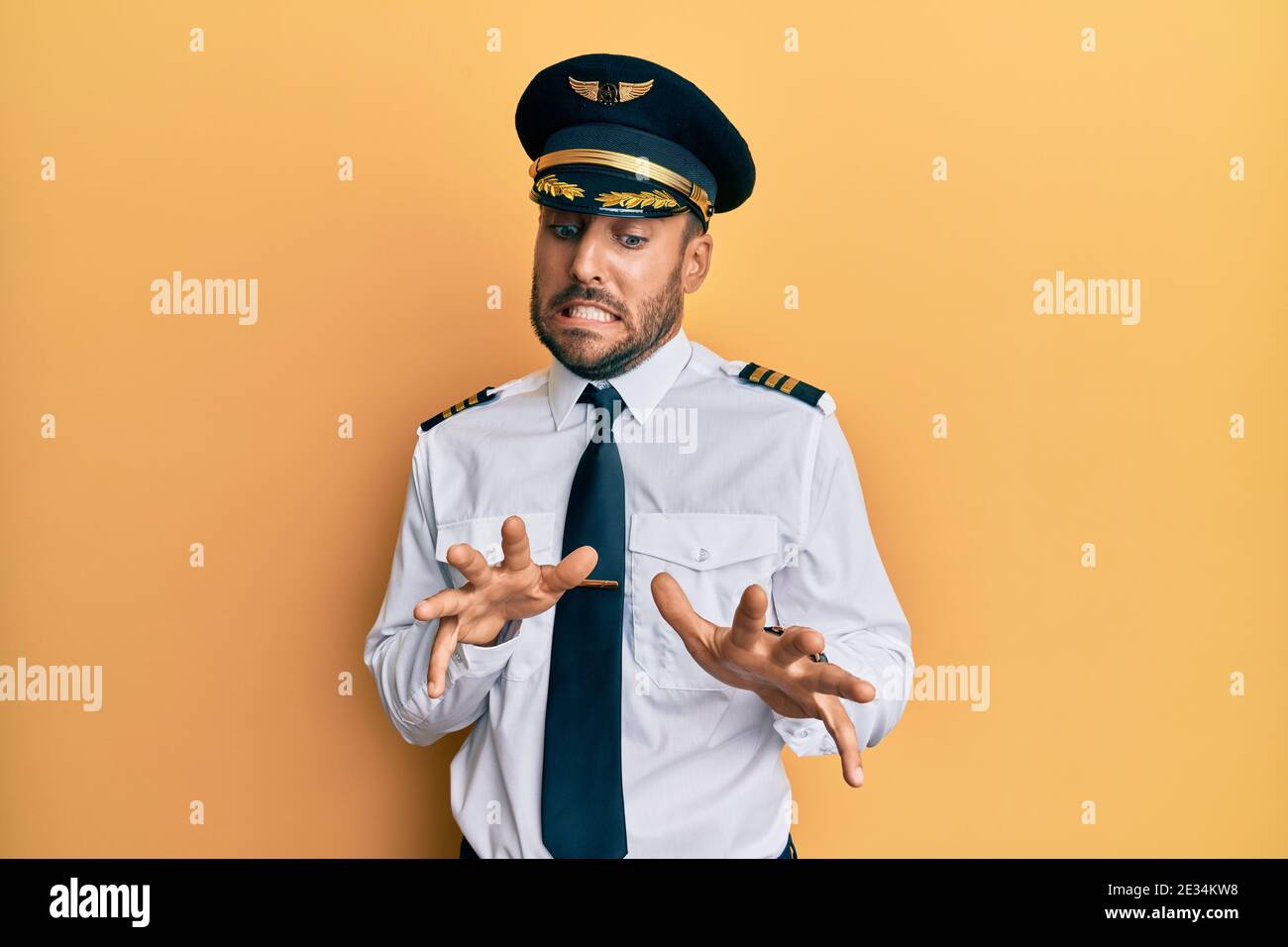 Handsome hispanic man wearing airplane pilot uniform disgusted ...