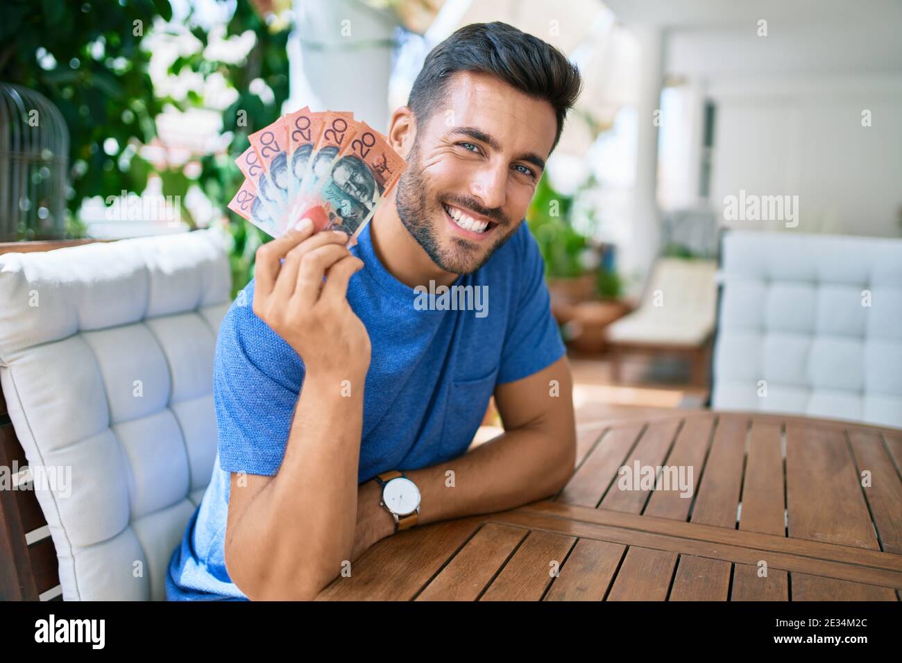 Young hispanic man smiling happy holding australian dollars banknotes ...