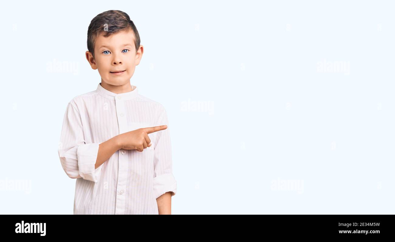 Cute blond kid wearing elegant shirt pointing aside worried and nervous ...