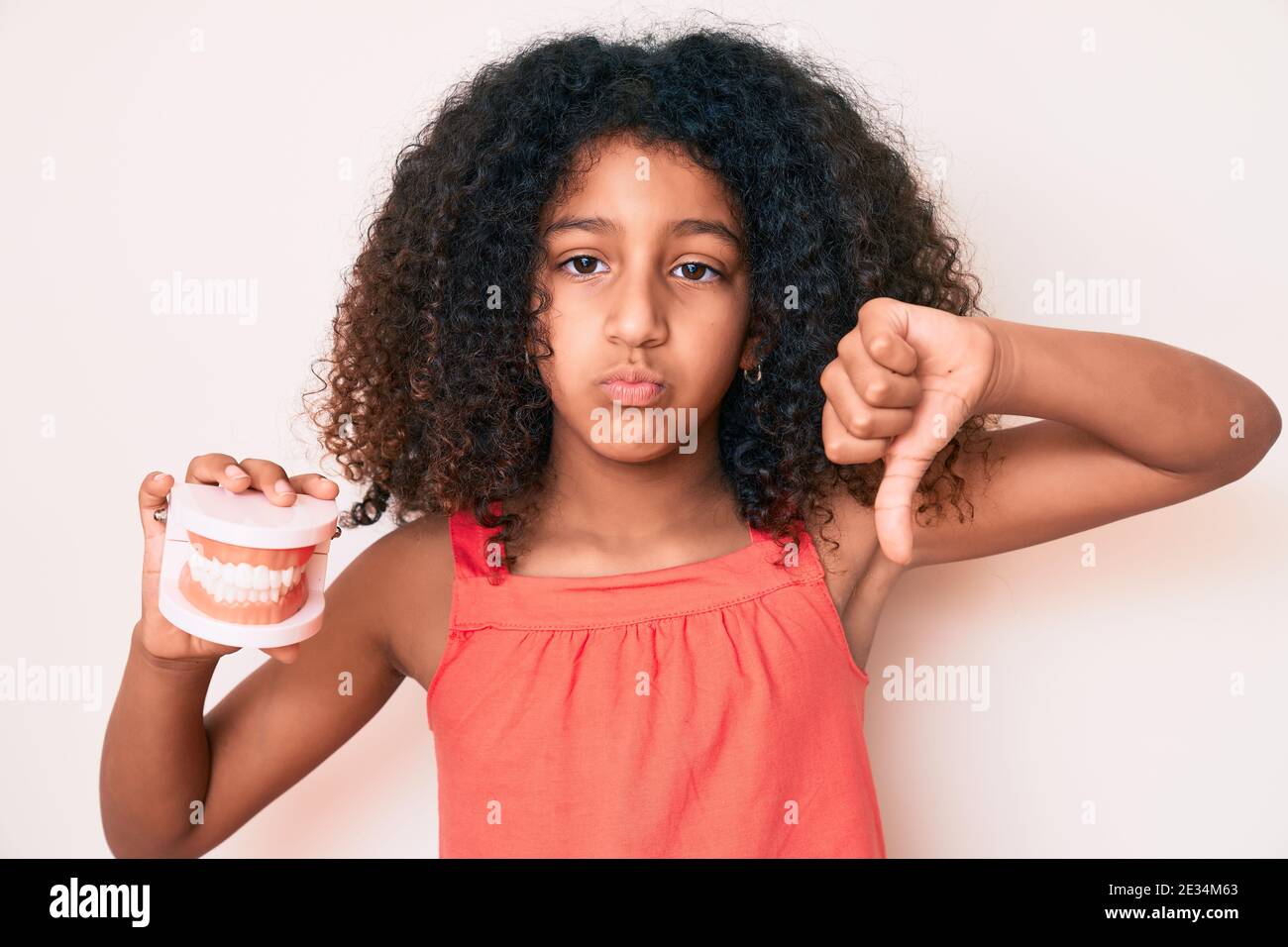 African american child with curly hair holding denture with angry face ...