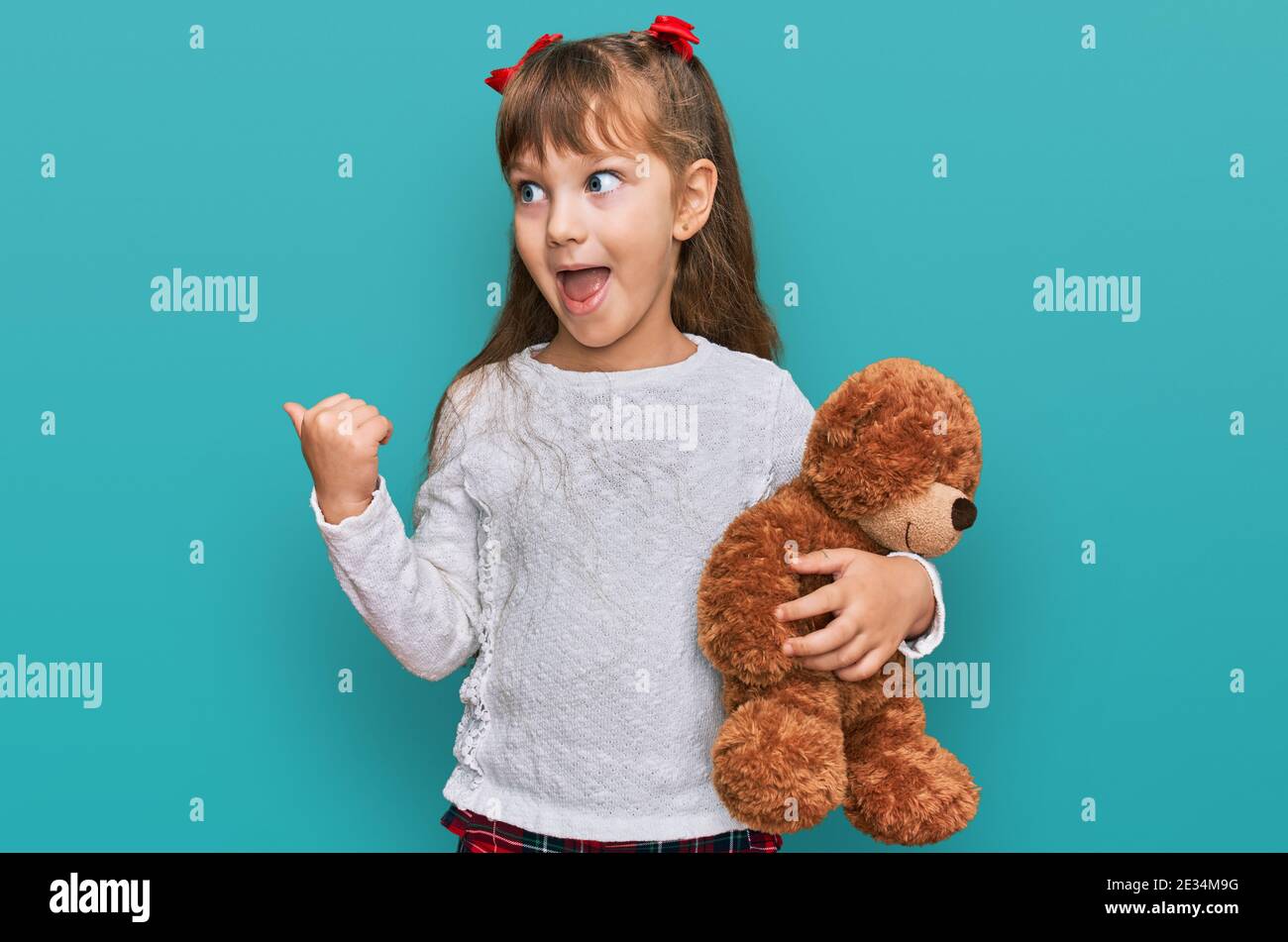 Little caucasian girl kid hugging teddy bear stuffed animal pointing ...