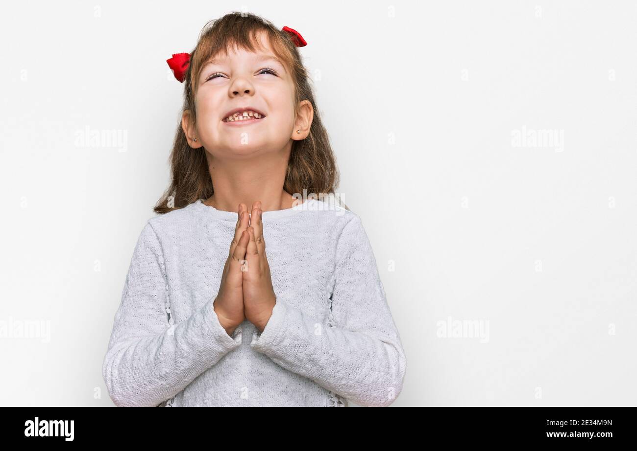 Little caucasian girl kid wearing casual clothes begging and praying ...