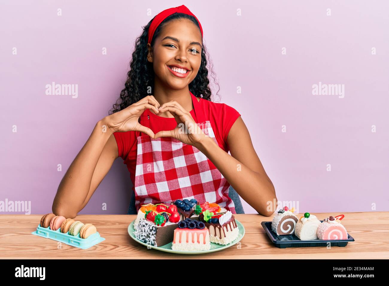 Young african american girl wearing baker uniform sitting on the table ...