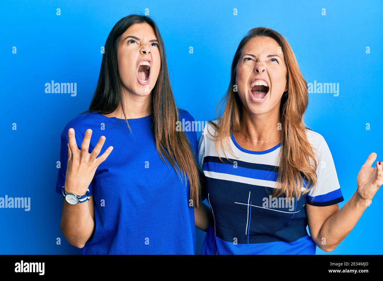Hispanic family of mother and daughter wearing casual clothes over blue ...