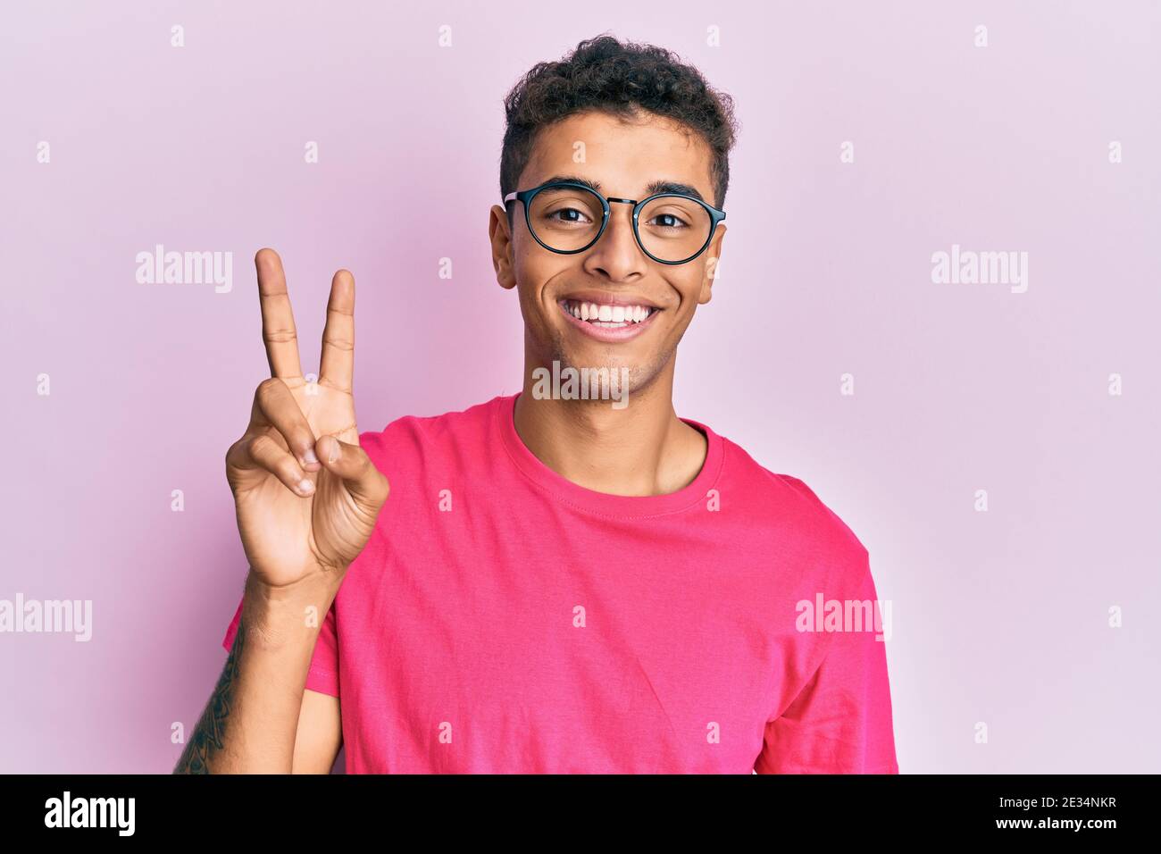 Young handsome african american man wearing glasses over pink ...