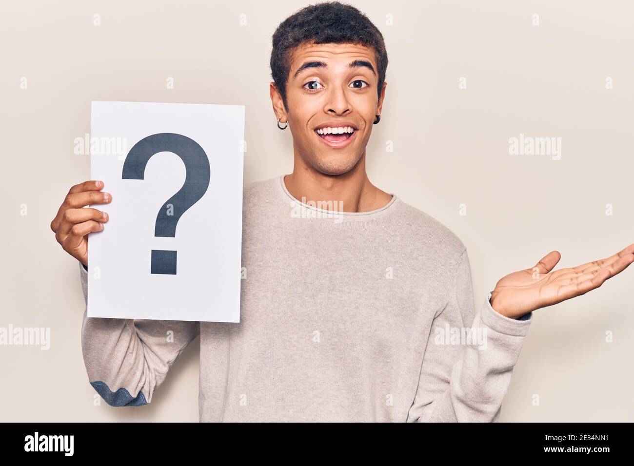 Young african amercian man holding question mark celebrating ...