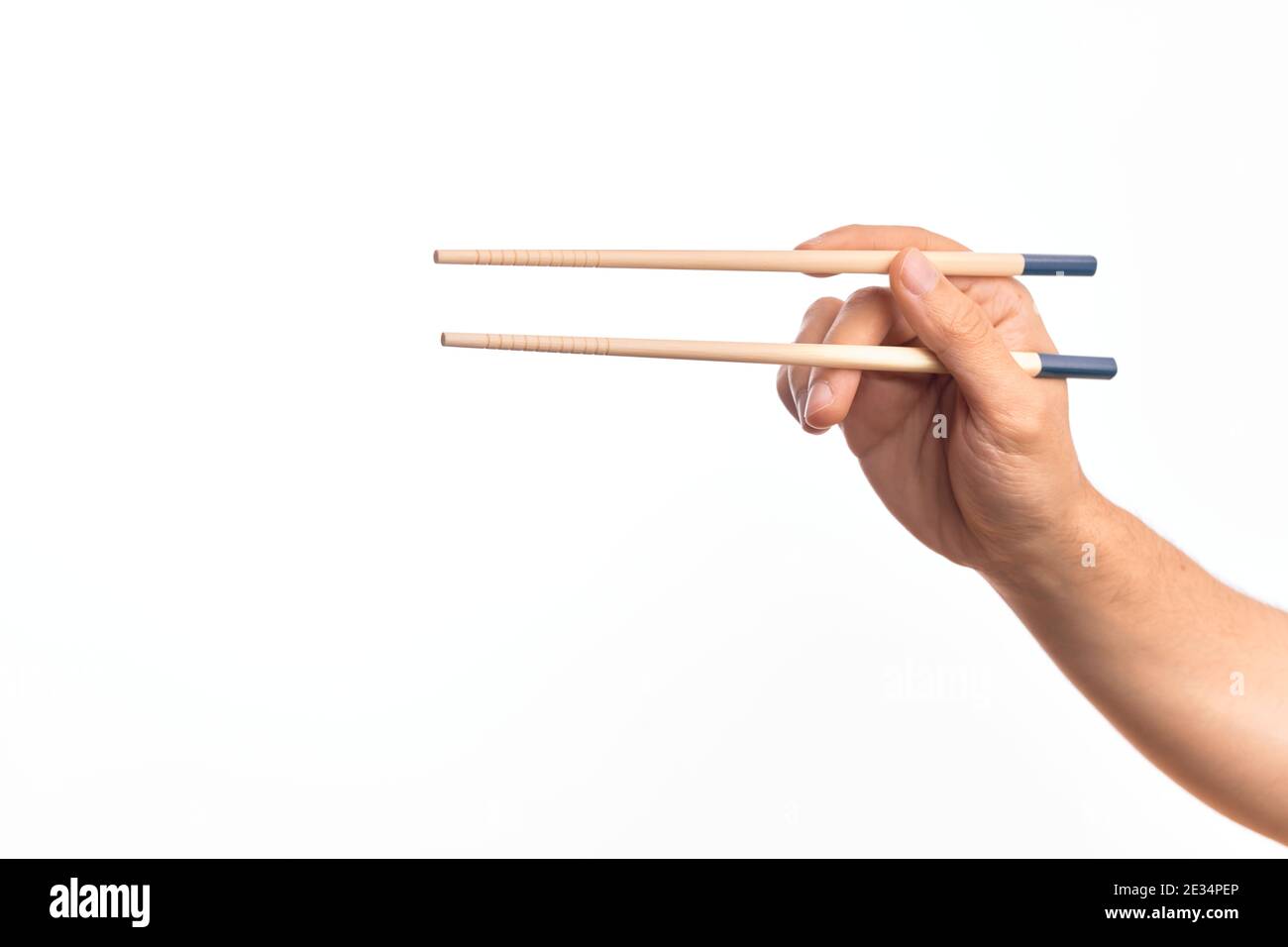 Hand of caucasian young man holding chopsticks over isolated white ...