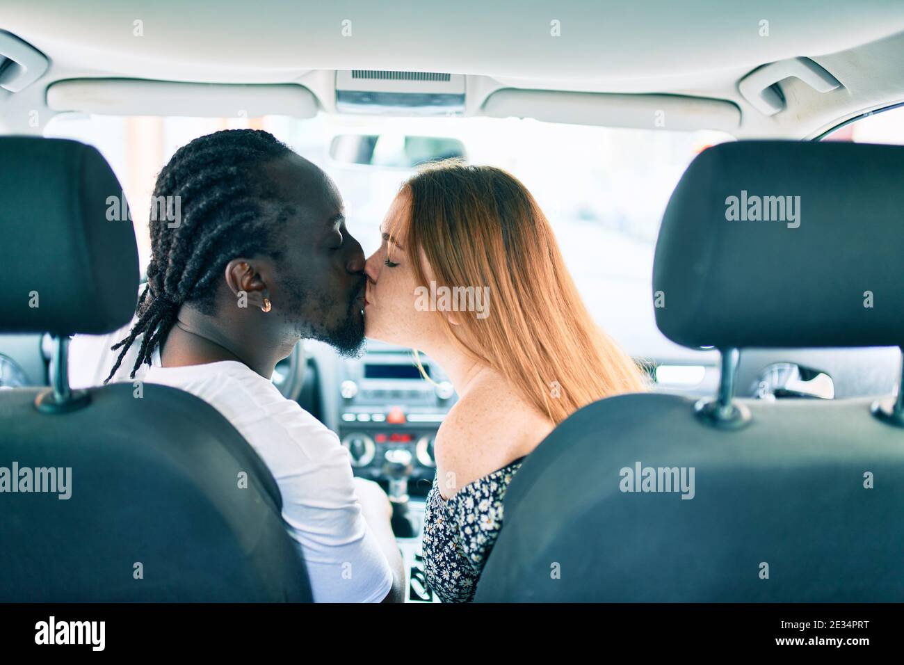 Young Interracial Couple Smiling Happy And Kissing At The Car Stock