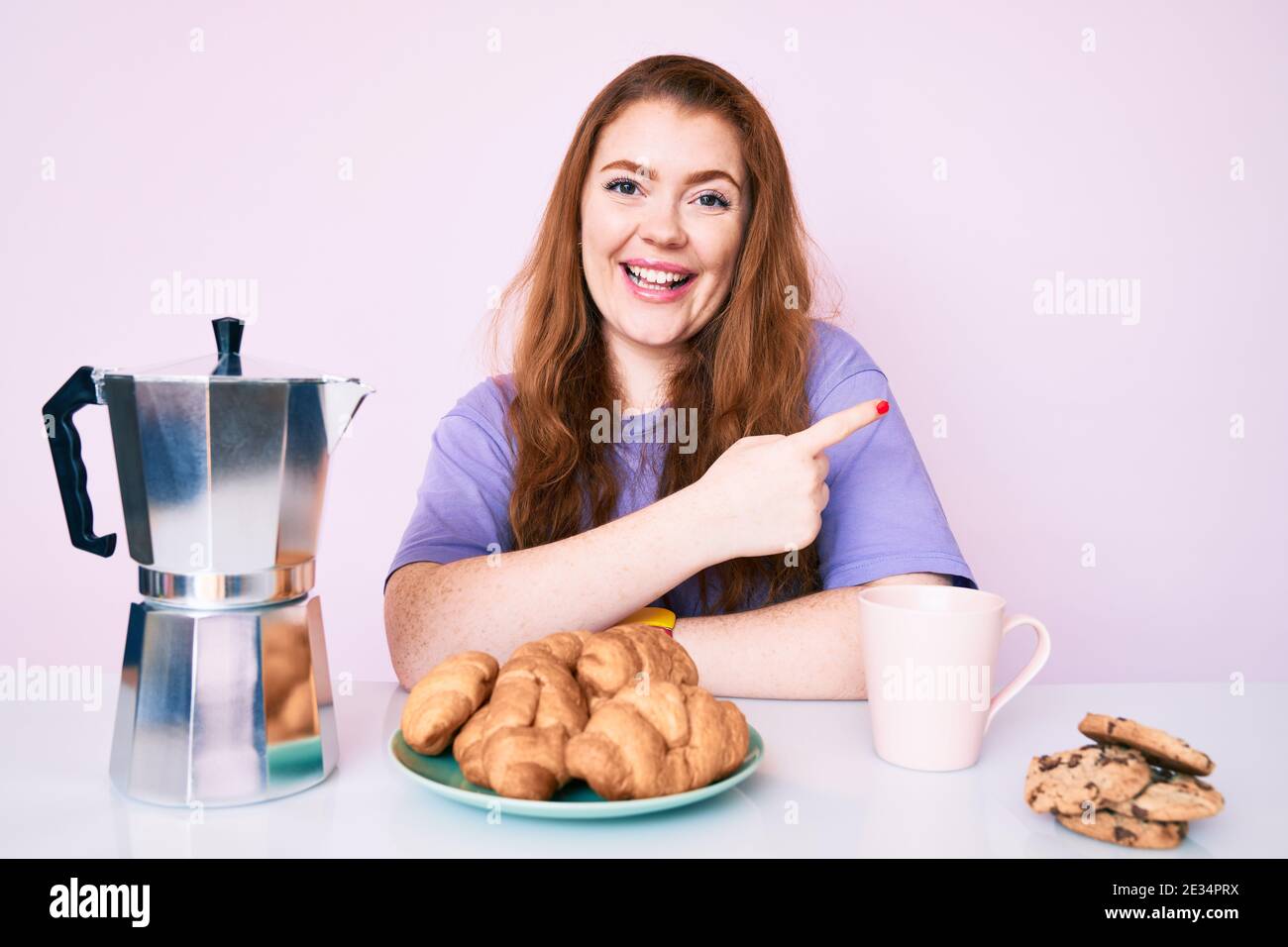 Young redhead woman eating breakfast looking positive and happy ...