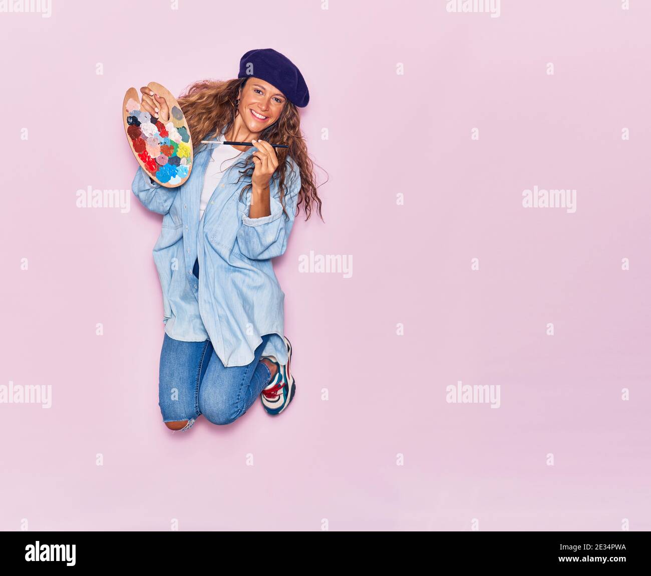 Young beautiful curly artist woman with tattoo wearing french beret ...