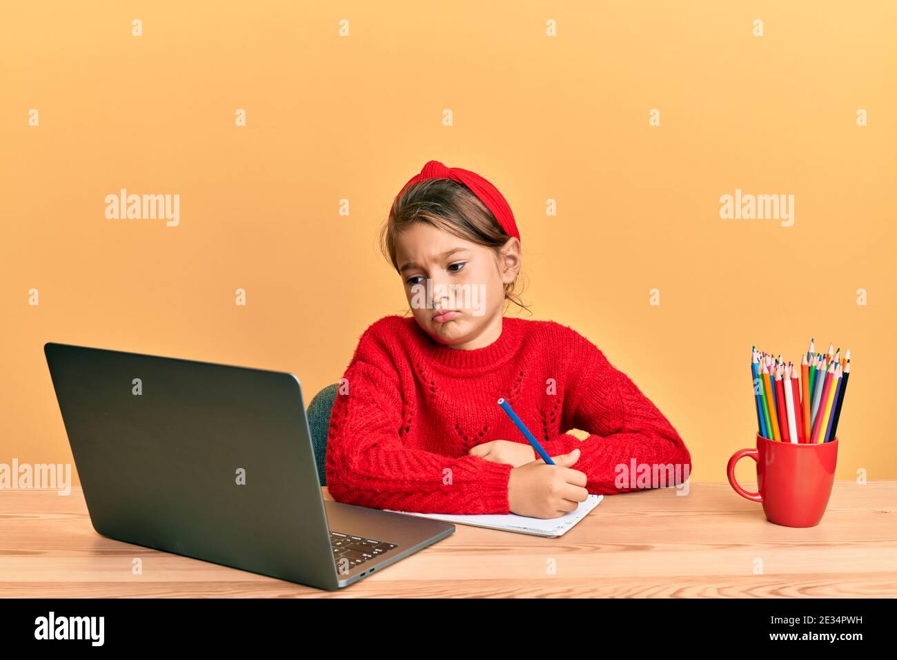 Little beautiful girl studying using computer laptop depressed and ...