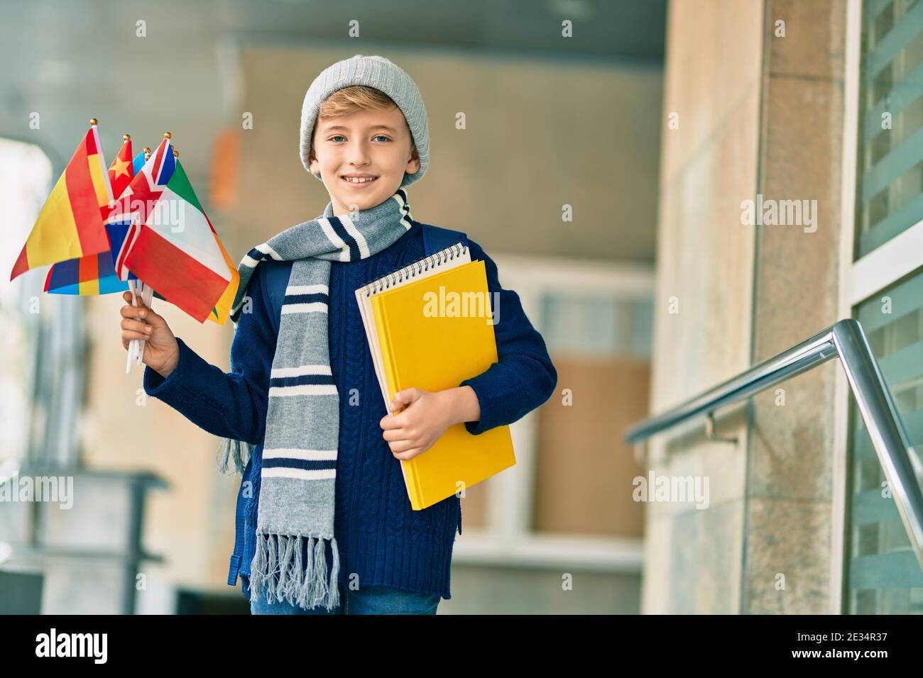 Adorable blond student kid smiling happy holding flags of different ...