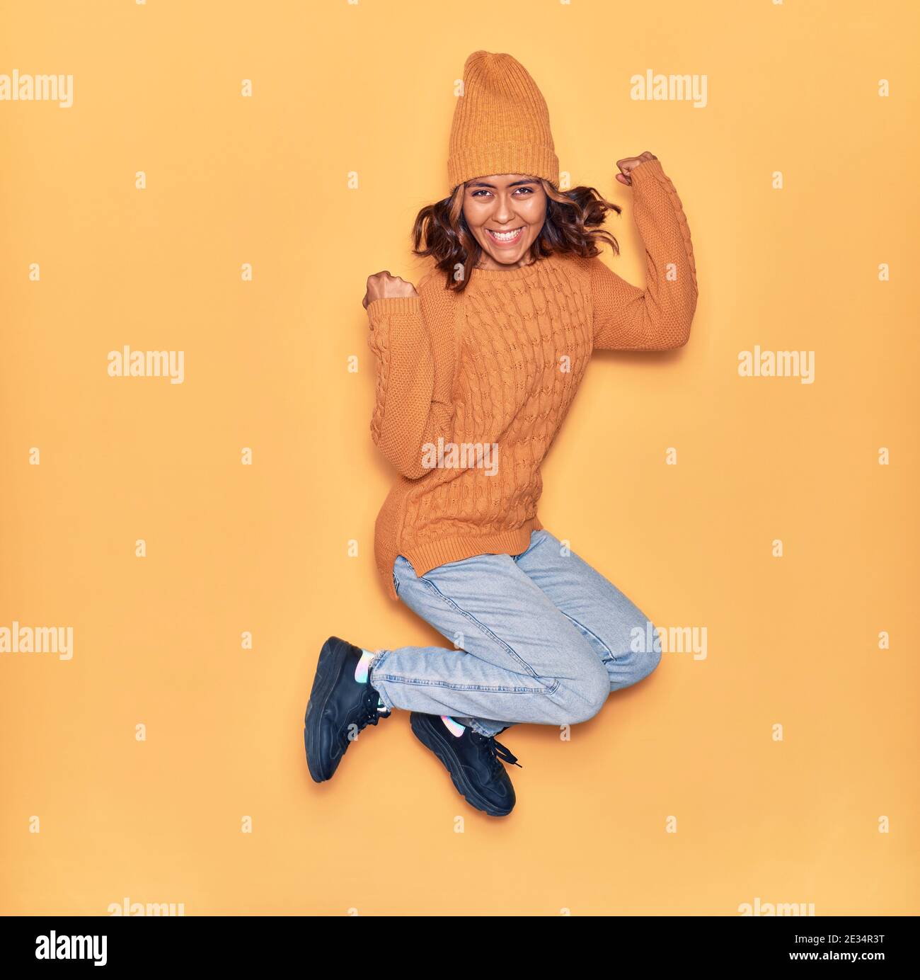 Young beautiful latin woman wearing wool cap and sweater smiling happy ...