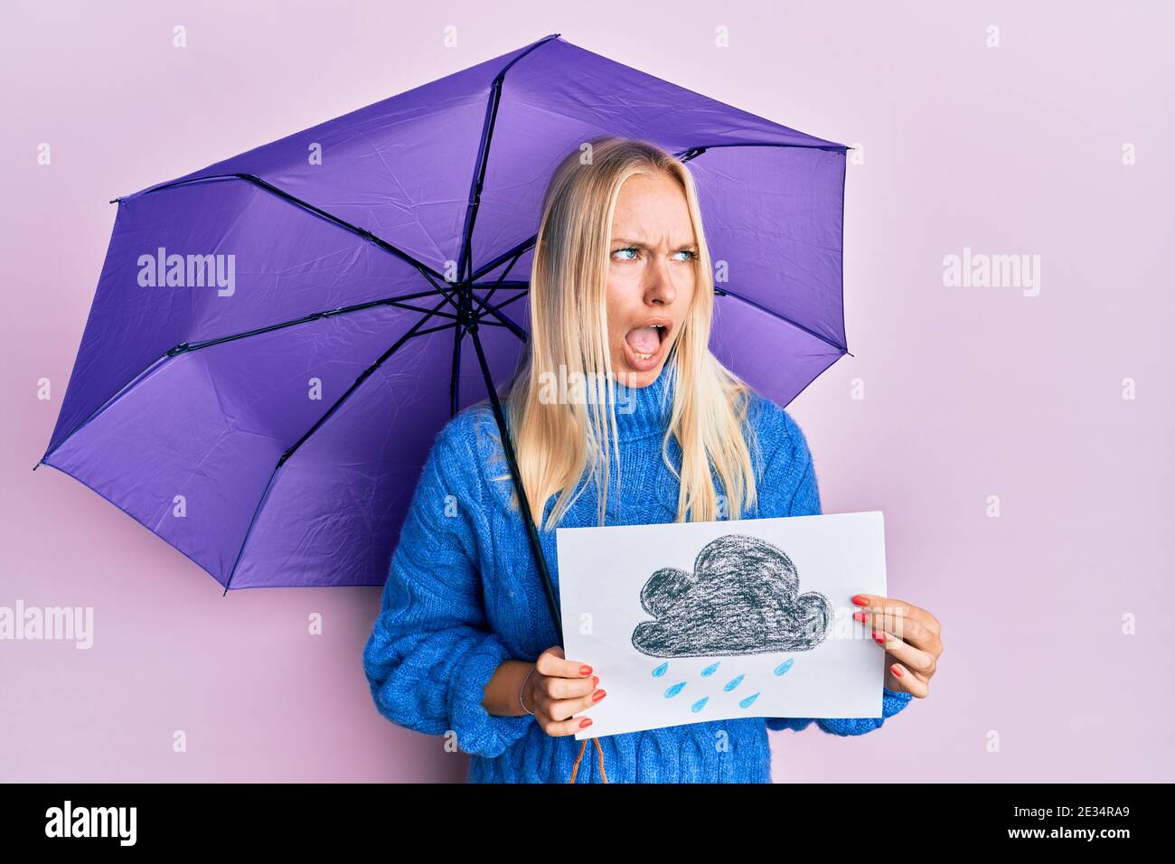 Young blonde girl holding umbrella rain draw angry and mad screaming ...